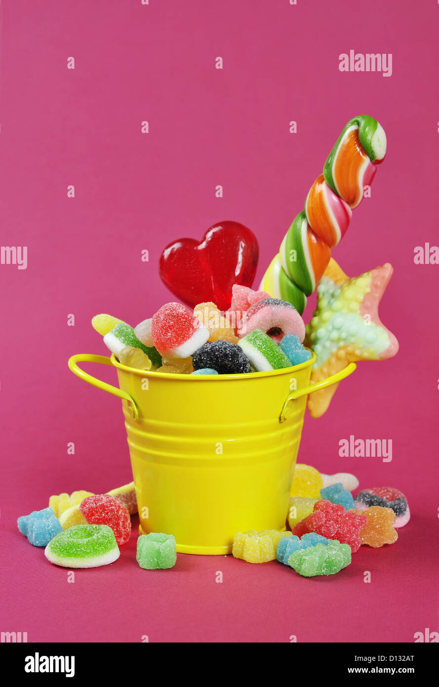 Colorful candies in yellow bucket on pink background Stock Photo - Alamy