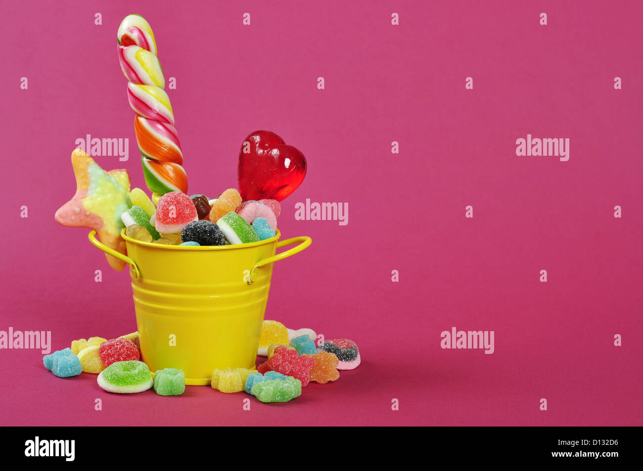 Colorful candies in yellow bucket on pink background Stock Photo - Alamy