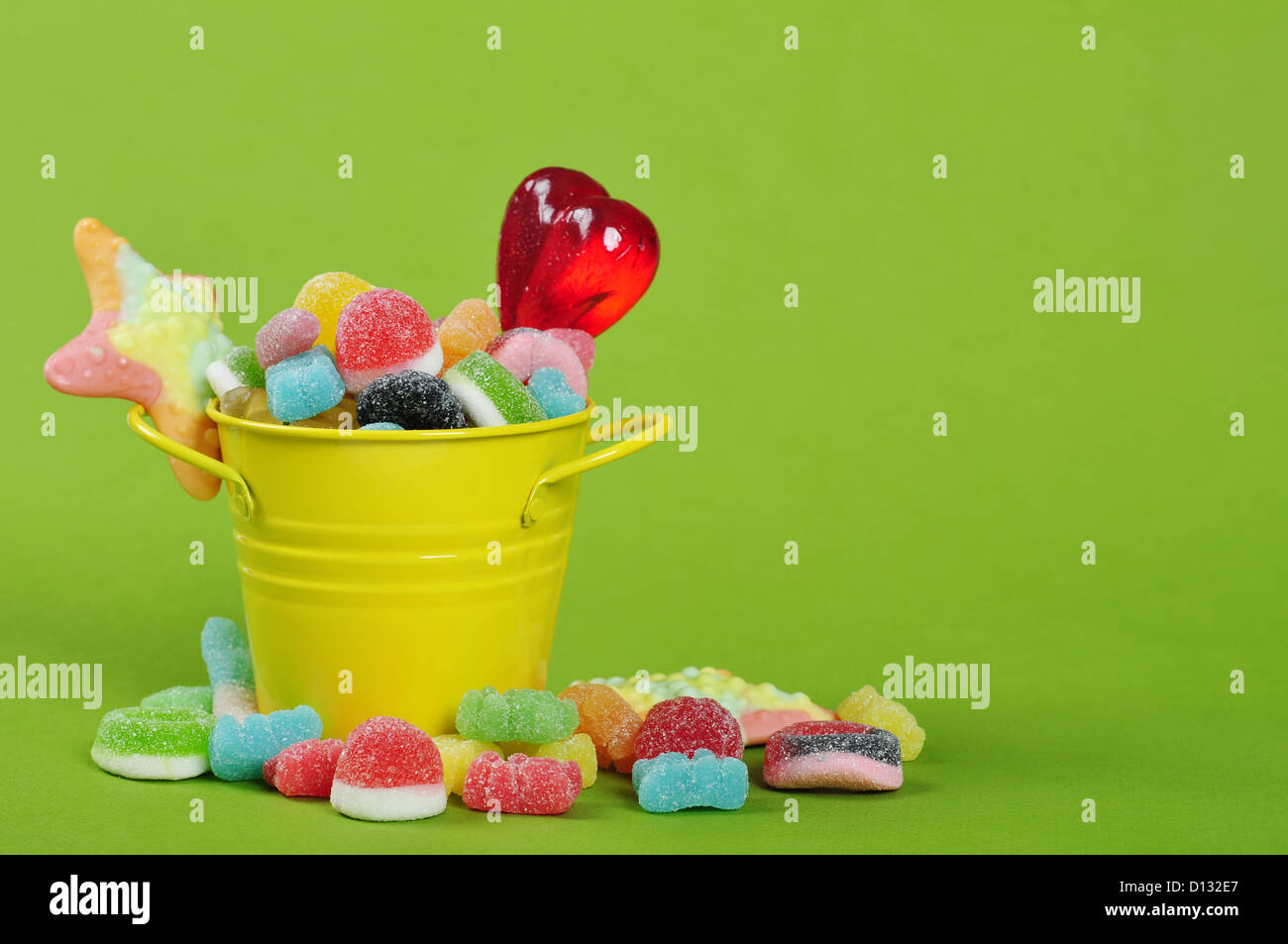 Colorful candies in yellow bucket on green background Stock Photo - Alamy
