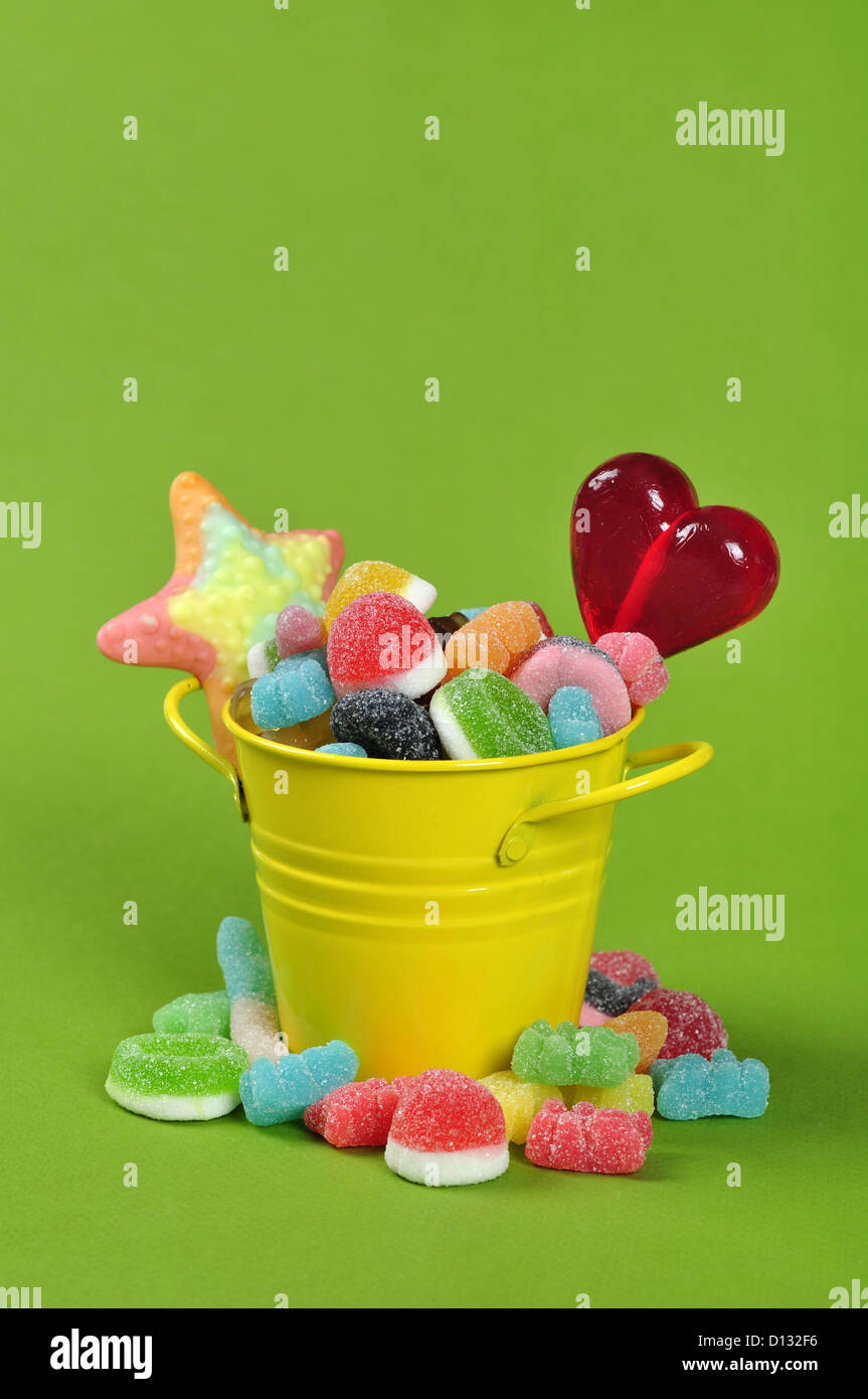 Colorful candies in yellow bucket on green background Stock Photo - Alamy