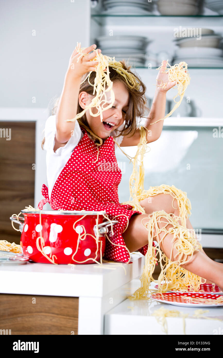 Germany, Girl playing with spaghetti on kitchen worktop Stock Photo - Alamy