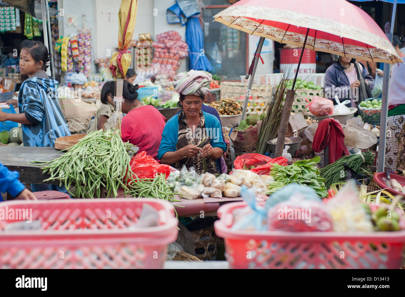 Balinese woman with a towel on her head ,tiding up her bench at an ...