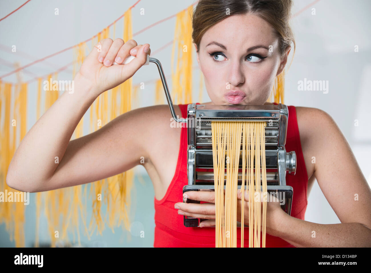 Germany, Young woman making pasta with machine Stock Photo - Alamy