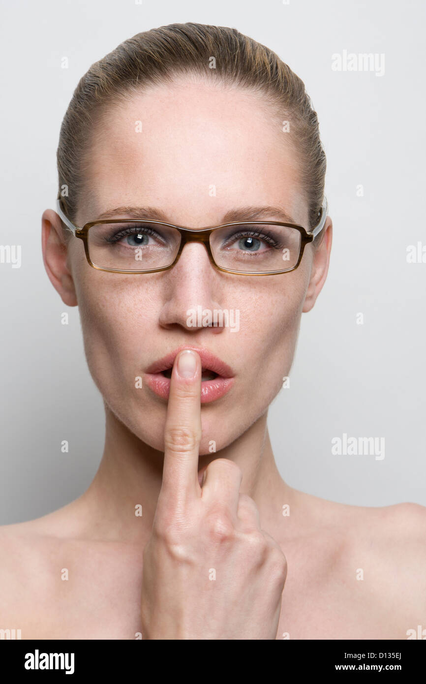 Young woman with finger on lips, close up Stock Photo - Alamy