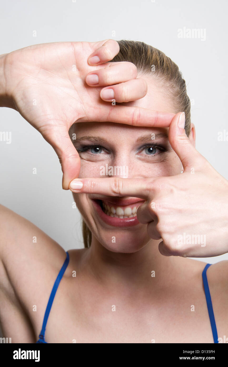 Young woman looking through finger frame, close up Stock Photo - Alamy