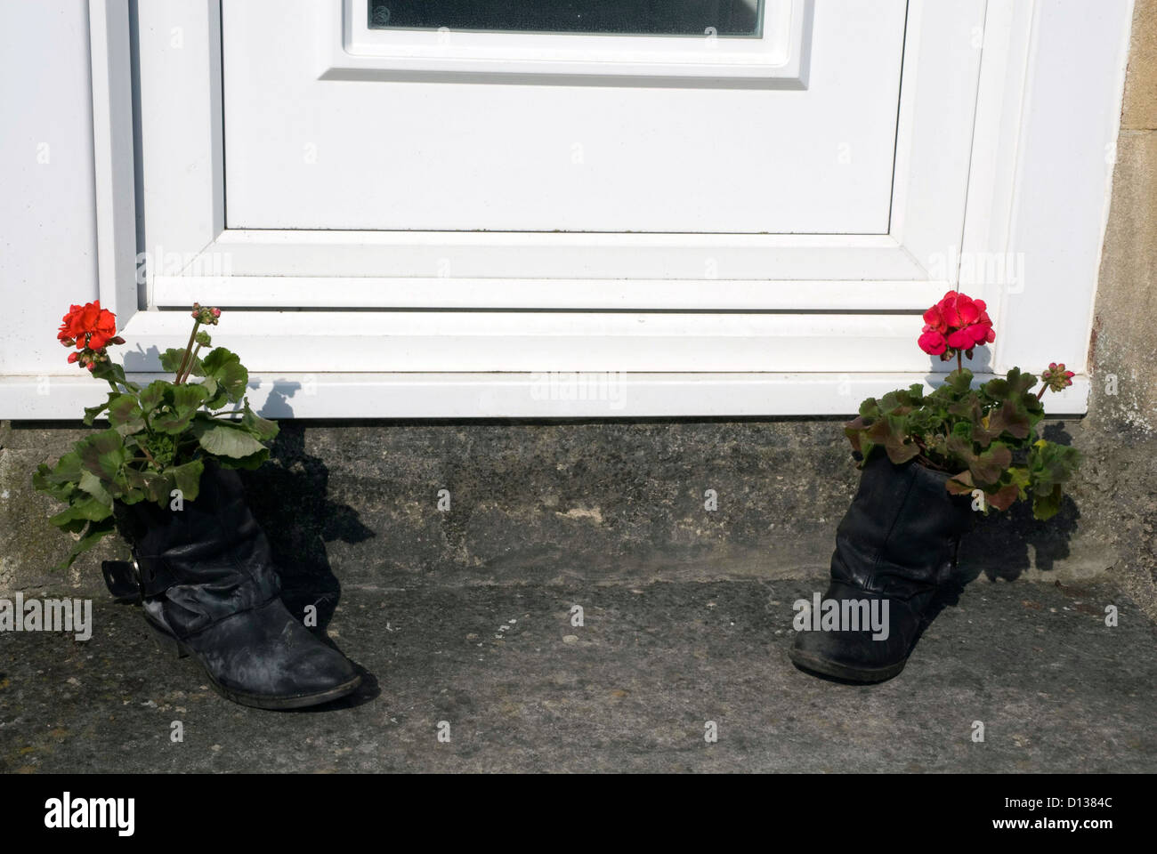 Old black boots used as flower pots on a door step in Bath, Somerset ...