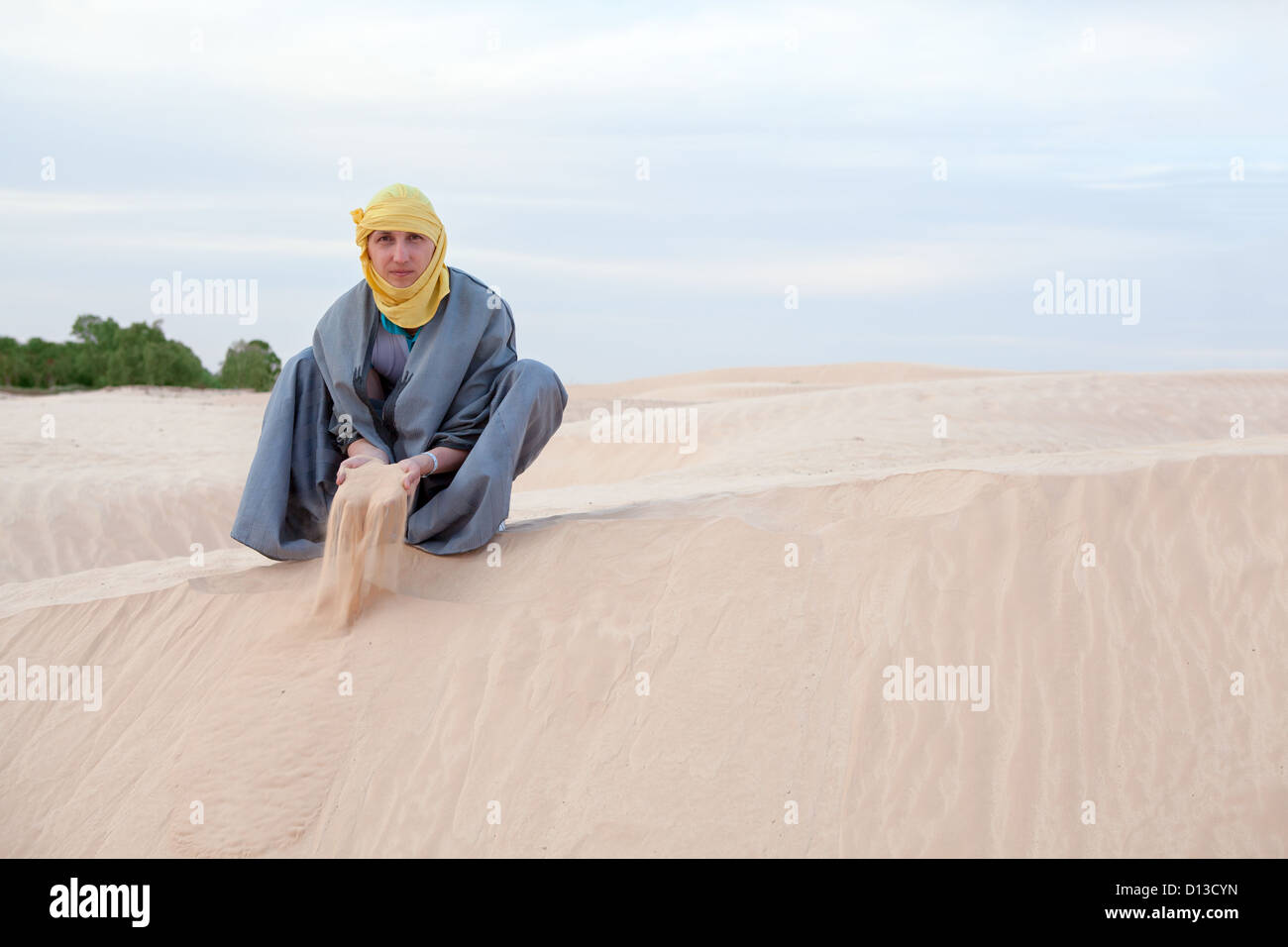 Caucasian person in protection eastern clothes pouring sand by hands on ...