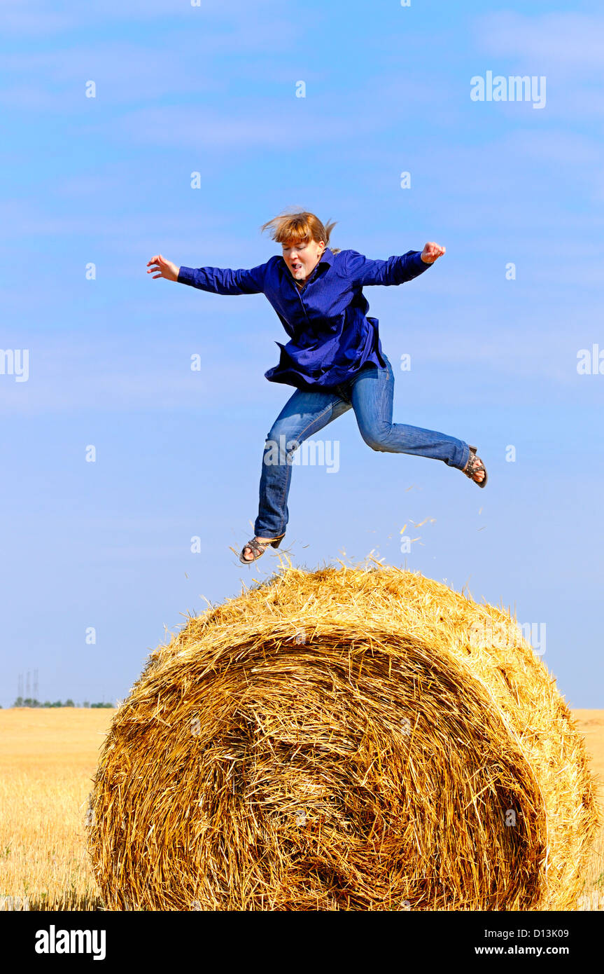 girl jumping up on straw roll Stock Photo - Alamy