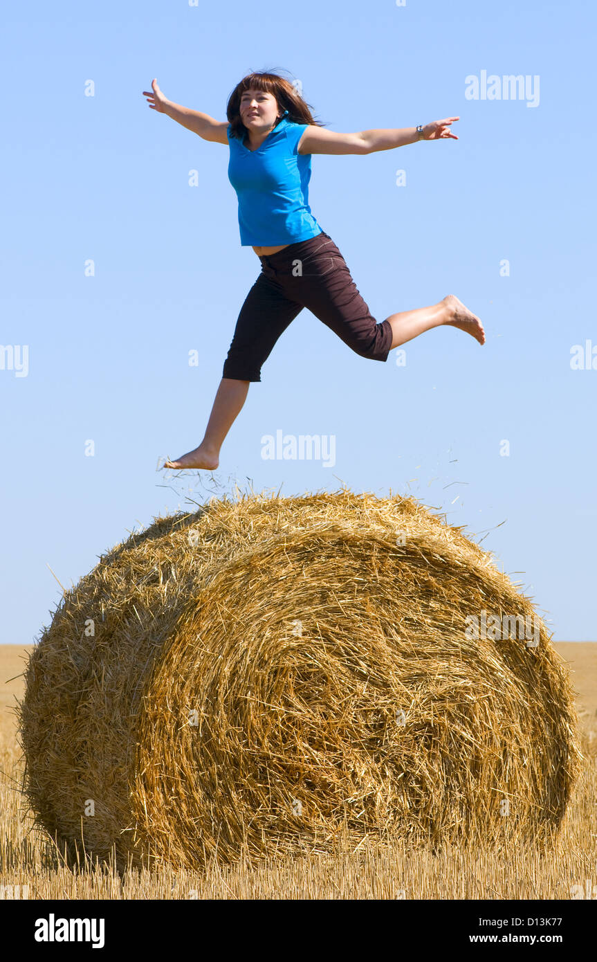 girl jumping up on straw roll Stock Photo - Alamy