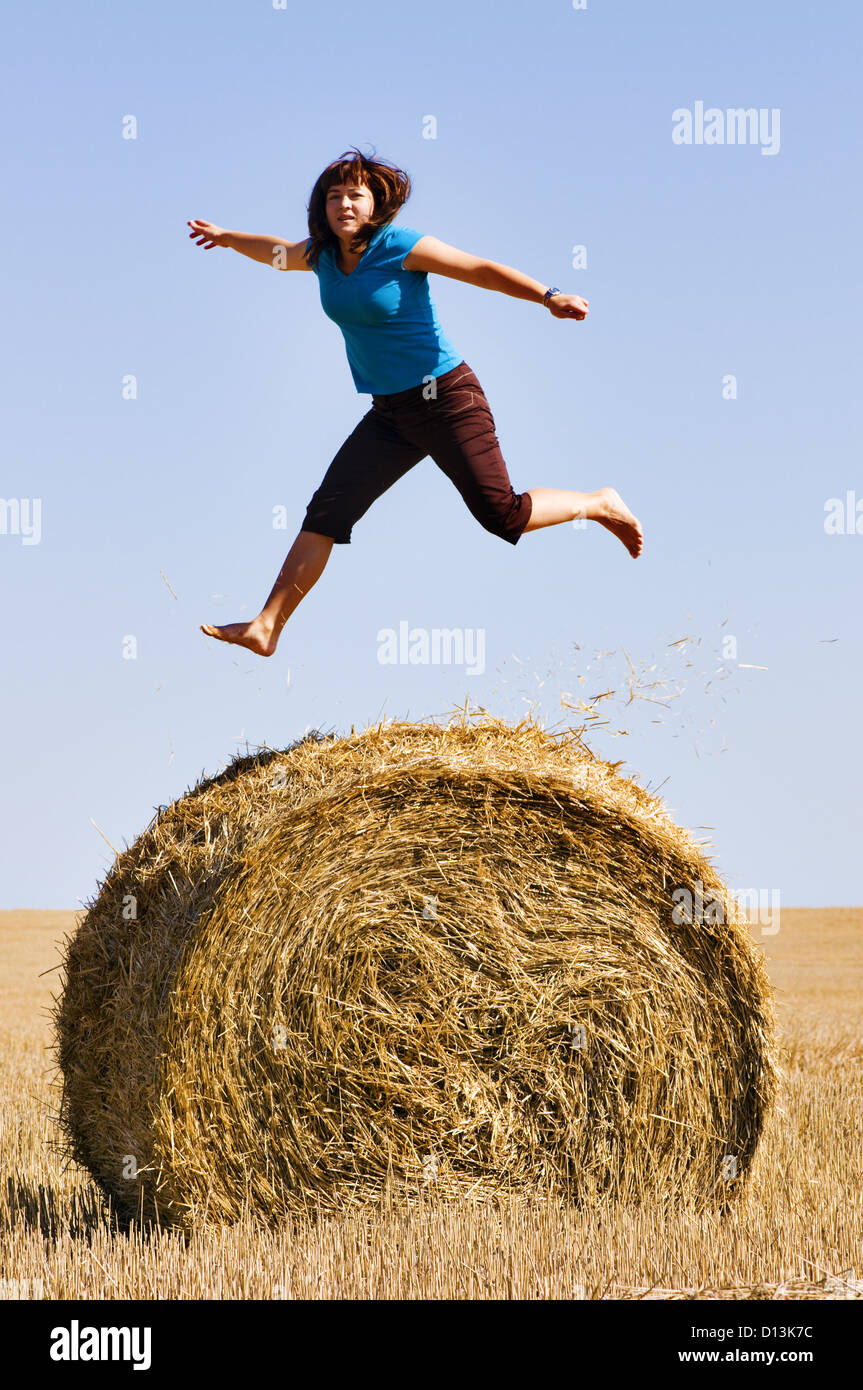 girl jumping up on straw roll Stock Photo - Alamy