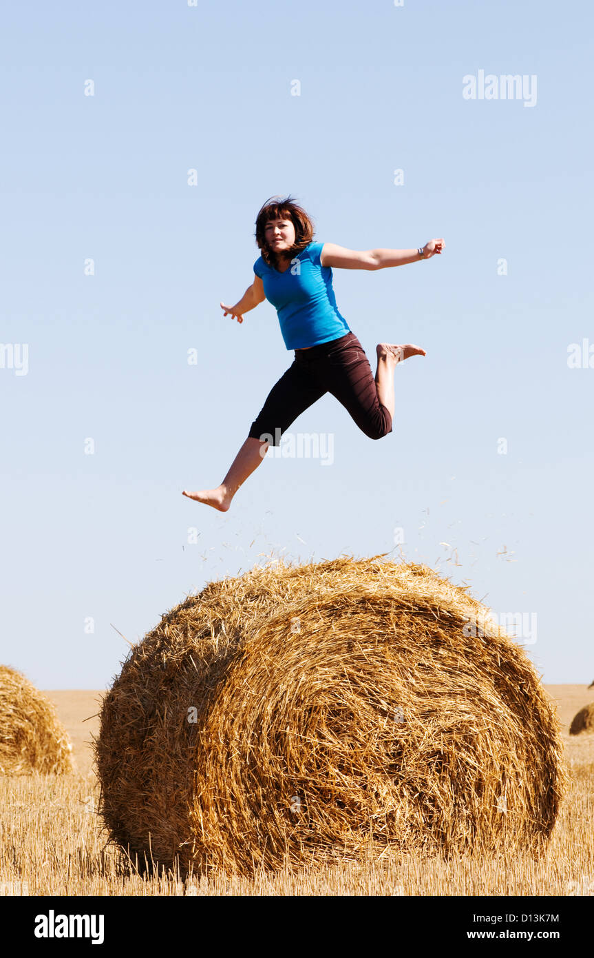 girl jumping up on straw roll Stock Photo - Alamy