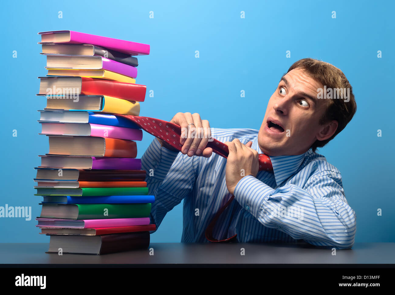man at the table looking with fear at a stack of colored books Stock ...