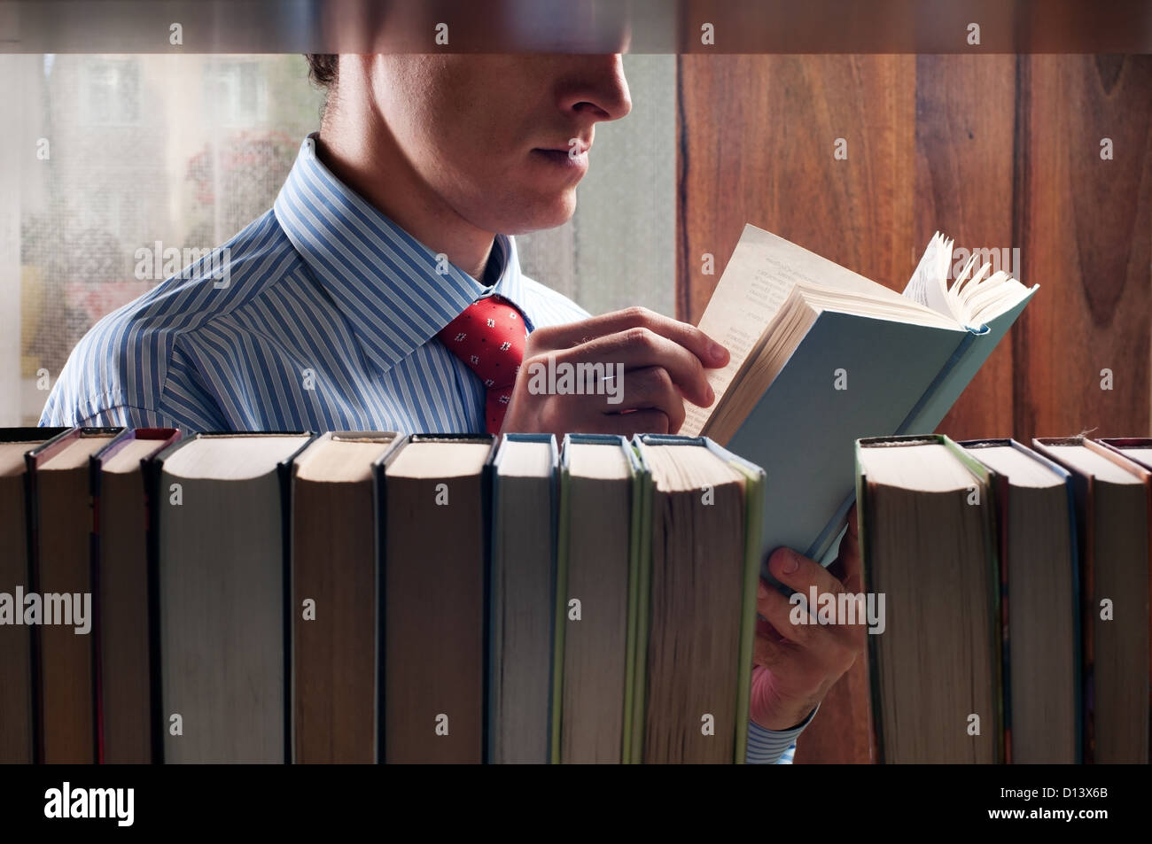 men reading a book next to the bookshelf Stock Photo - Alamy