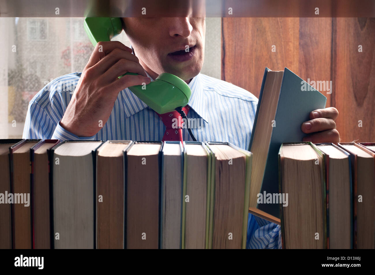 men talking by phone and a book next to the bookshelf Stock Photo - Alamy