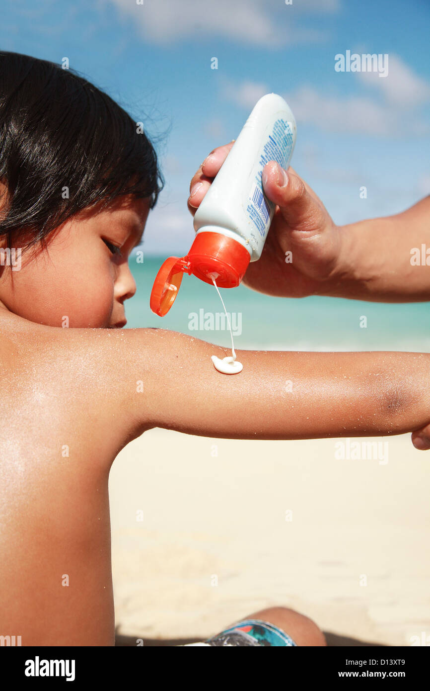 Hawaii, Oahu, Parent Putting Sunscreen Lotion On Child's Arm At The ...