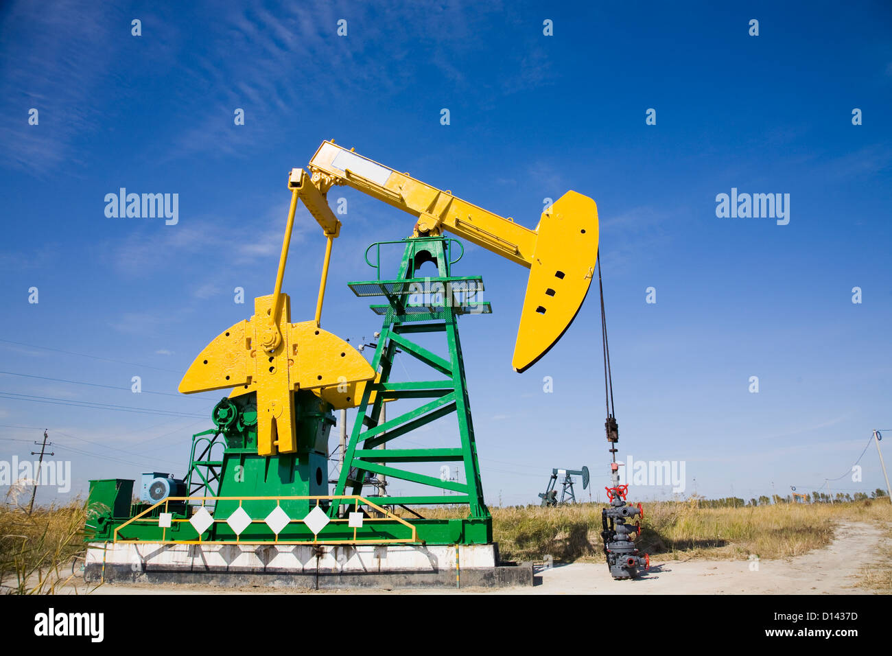 Yellow oil pump jack under blue sky Stock Photo - Alamy