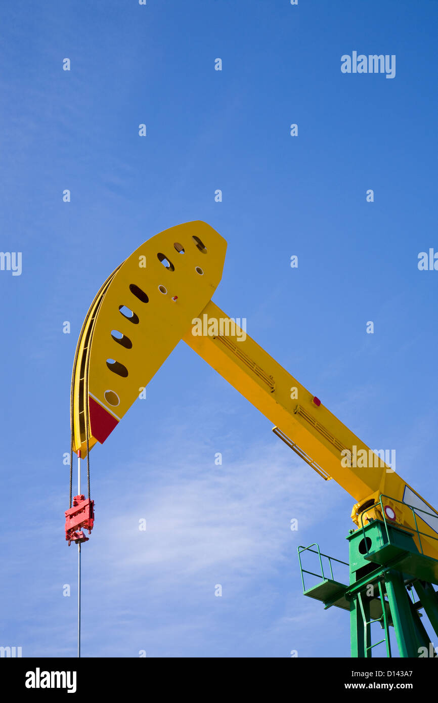 Yellow oil pump jack under blue sky Stock Photo - Alamy