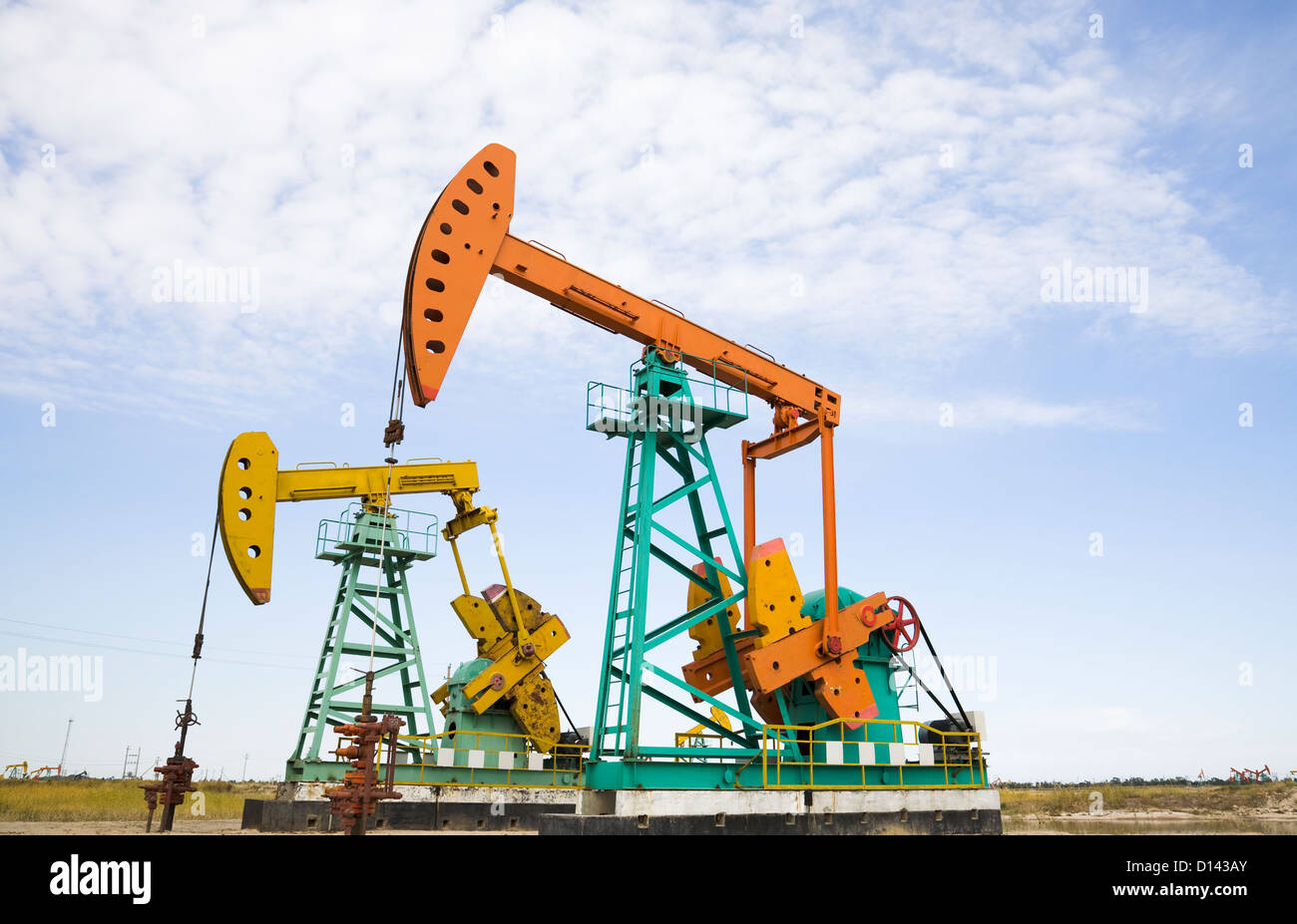 Yellow oil pump jack under blue sky Stock Photo - Alamy