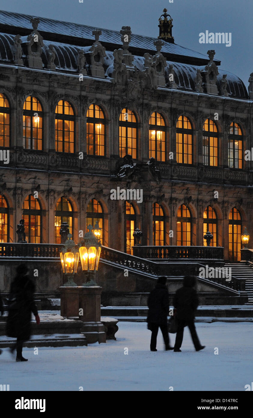 Tourists walk through the snow-covered Zwinger with the brightly lit ...