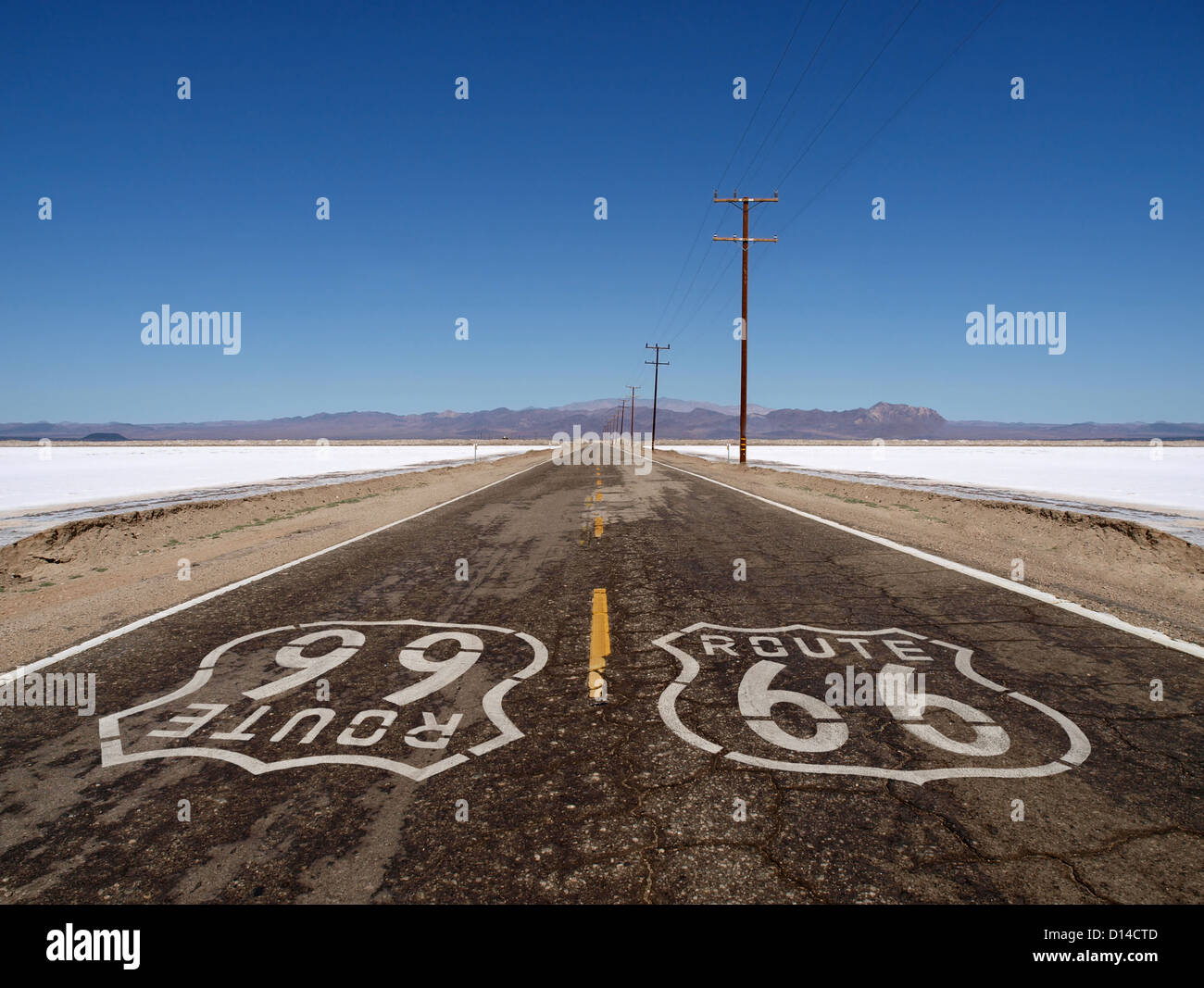 Route 66 sign painted on rough Mojave desert salt flat highway pavement ...