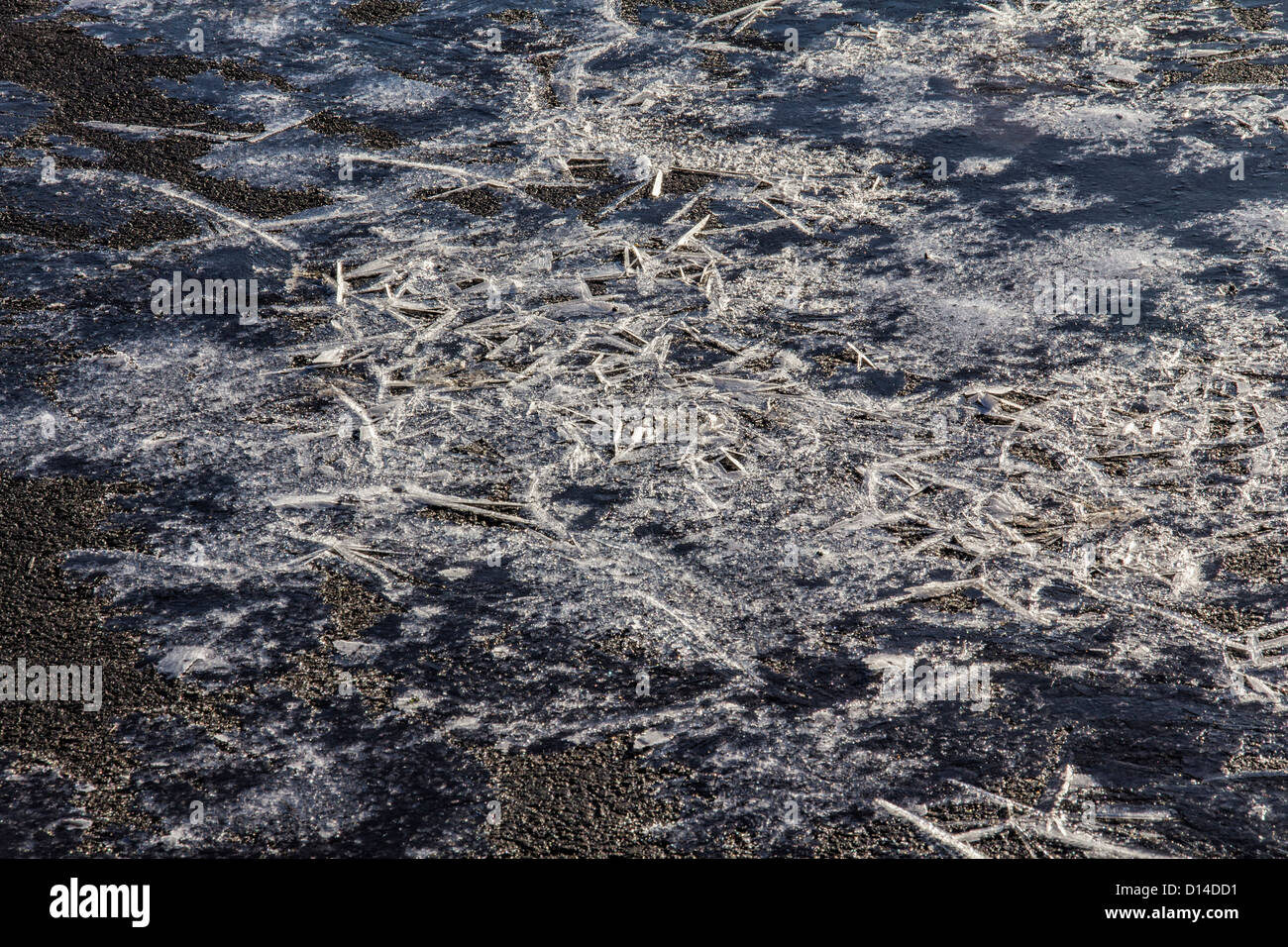 Oil and Ice crystals form a slippery surface on tar road a cold Winter ...