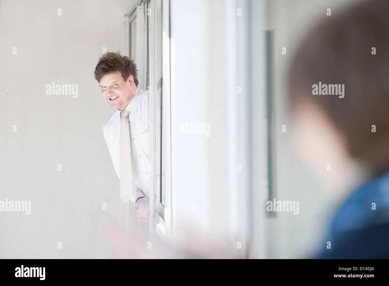 Businessman leaning out window Stock Photo - Alamy