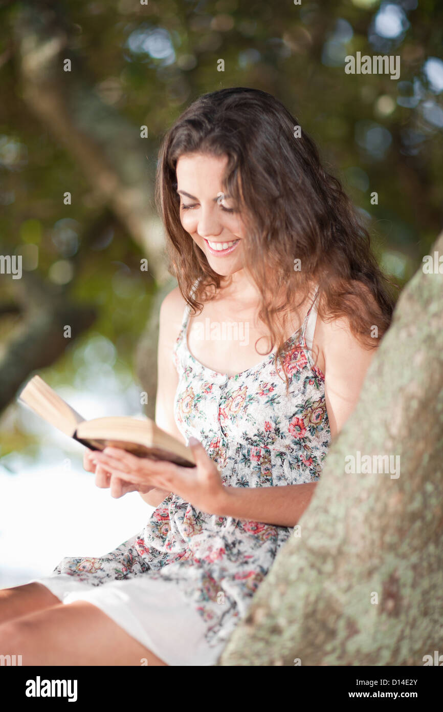 Woman reading book in tree outdoors Stock Photo - Alamy