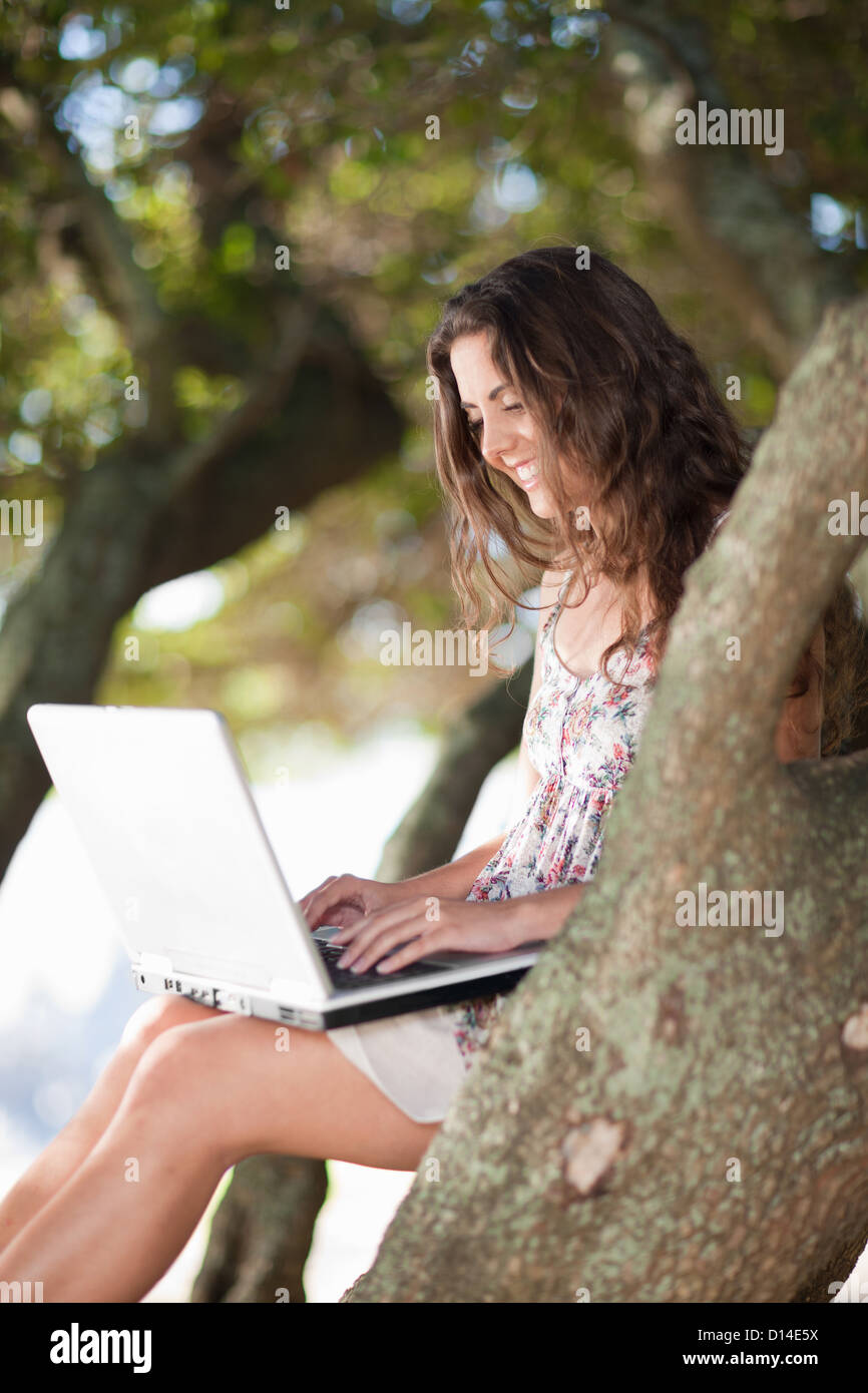 Woman using laptop in tree outdoors Stock Photo - Alamy