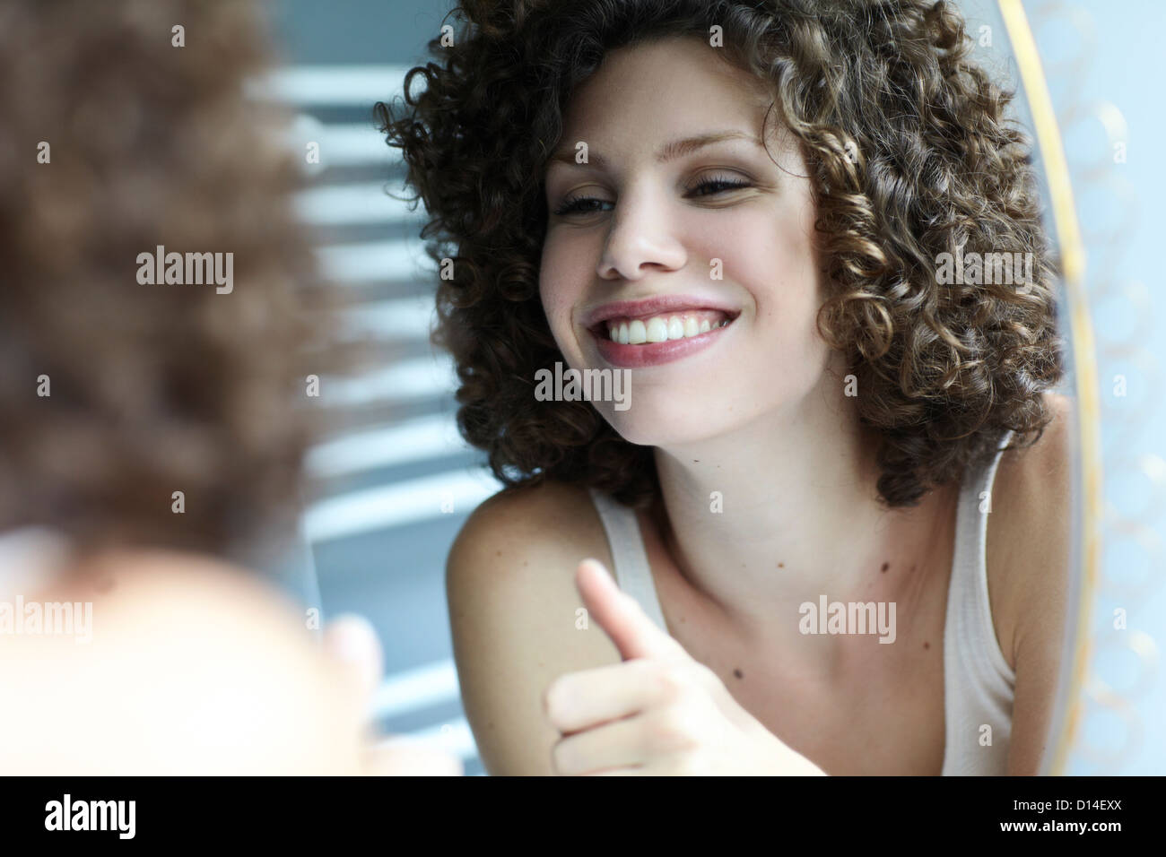young woman smiling at her reflection in the mirror Stock Photo - Alamy