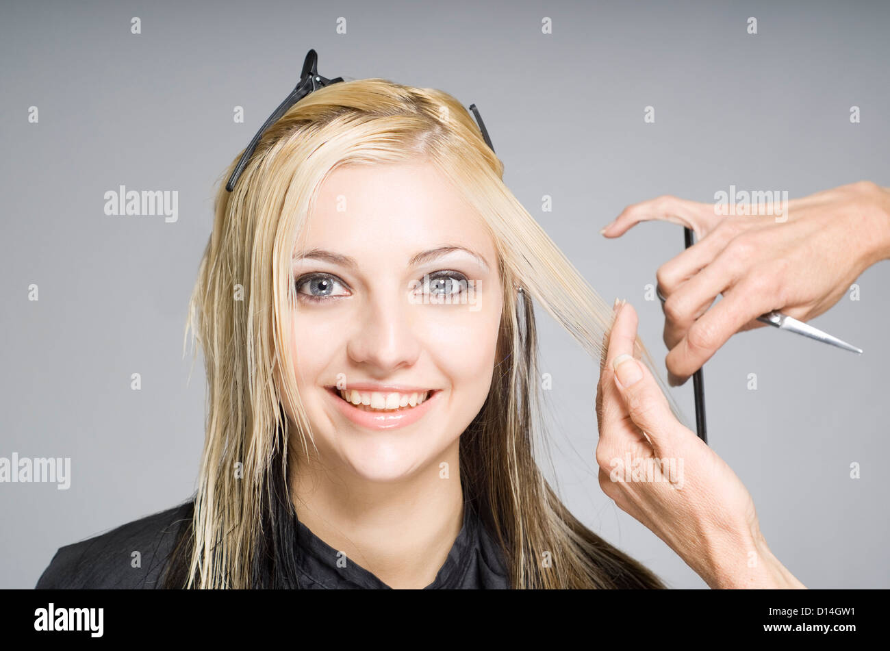 Smiling happy hair client or customer while hairdresser cutting hair ...