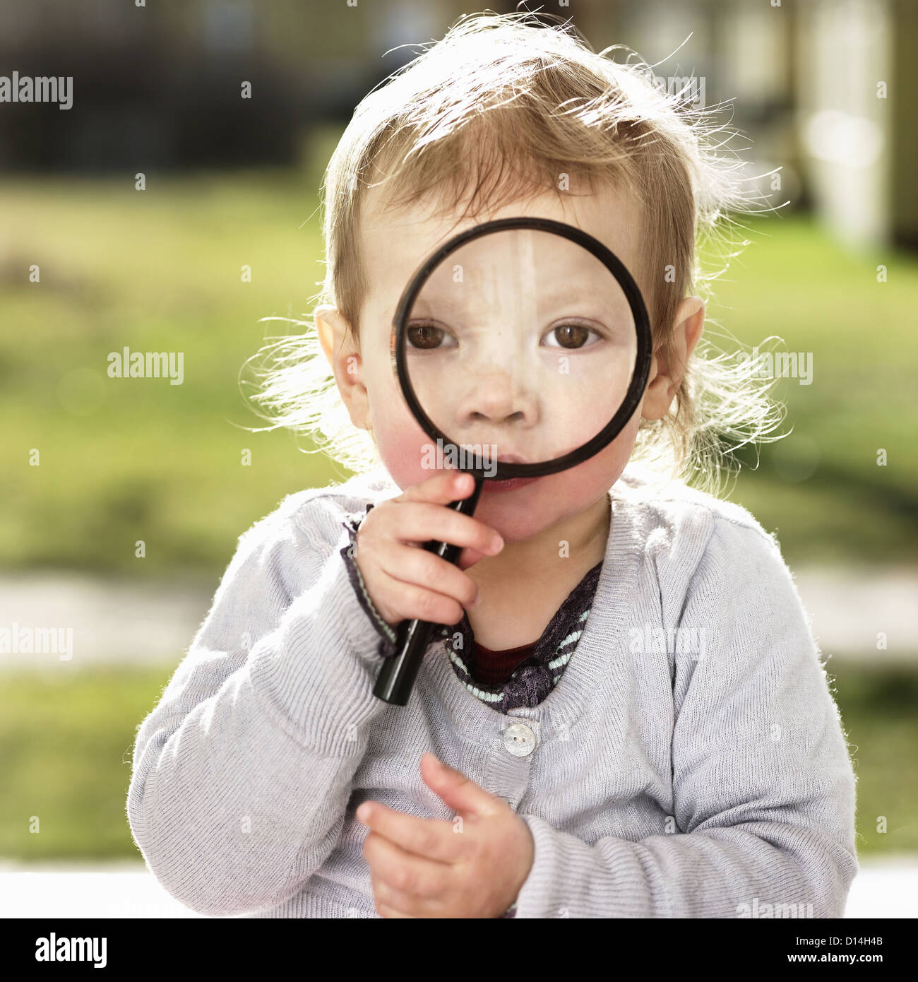 Toddler girl holding magnifying glass Stock Photo - Alamy