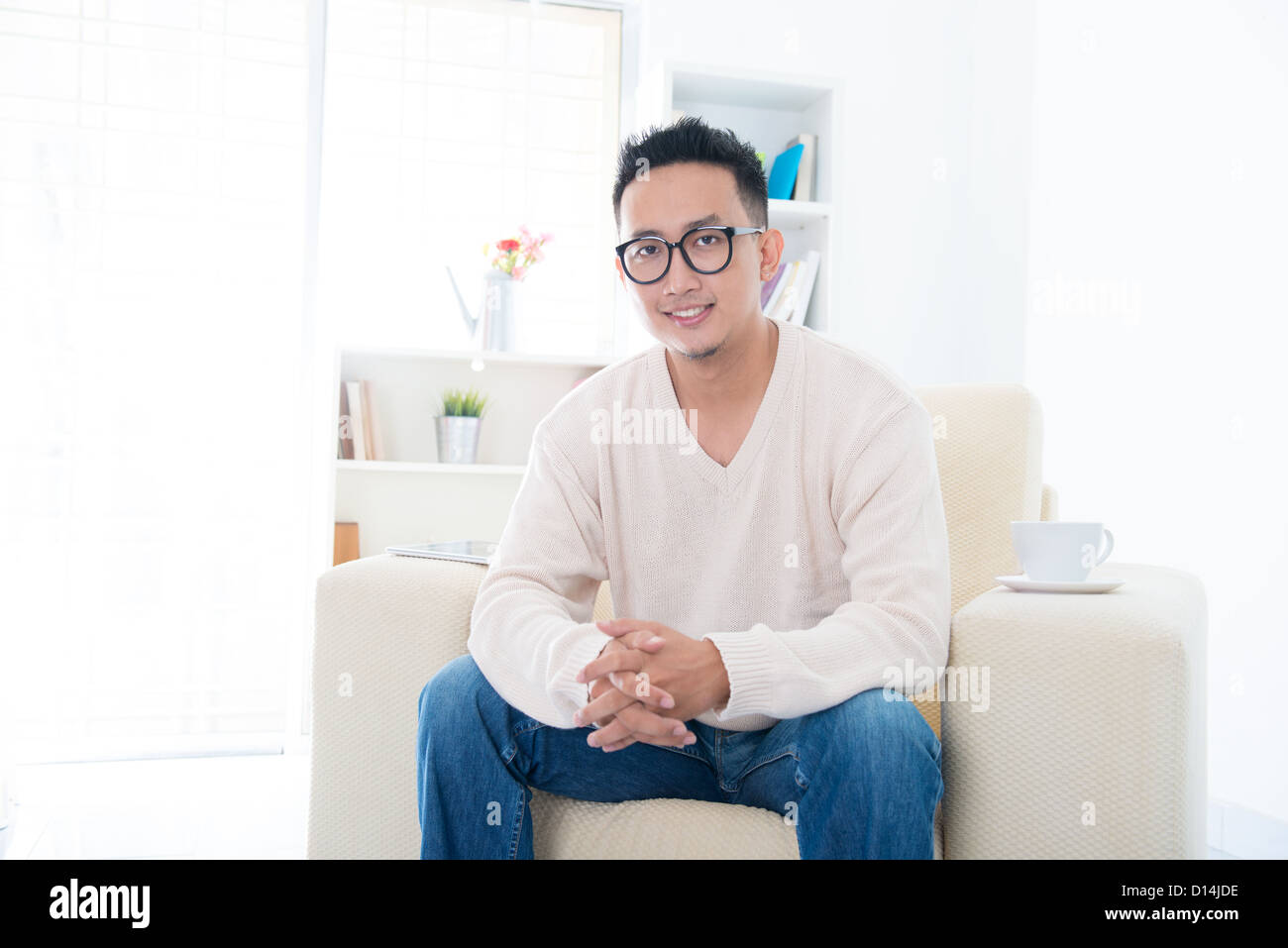 Southeast Asian male sitting on sofa at home Stock Photo - Alamy