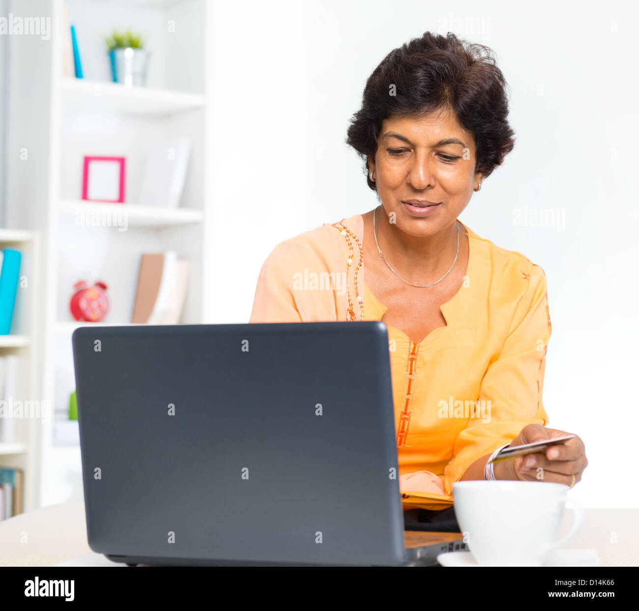 Mature 50s Indian woman holding credit card online shopping at home ...