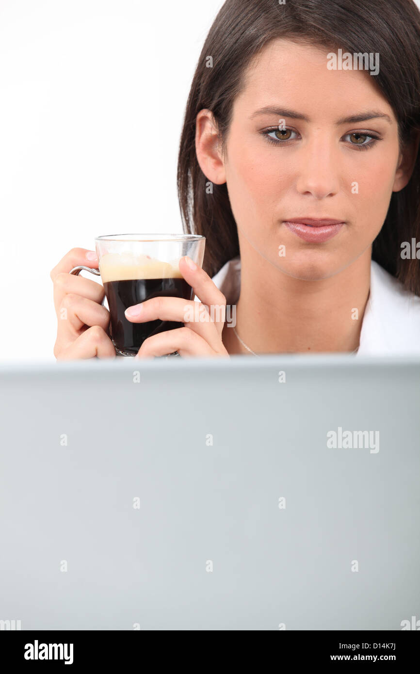 Woman drinking coffee while working at her laptop Stock Photo - Alamy