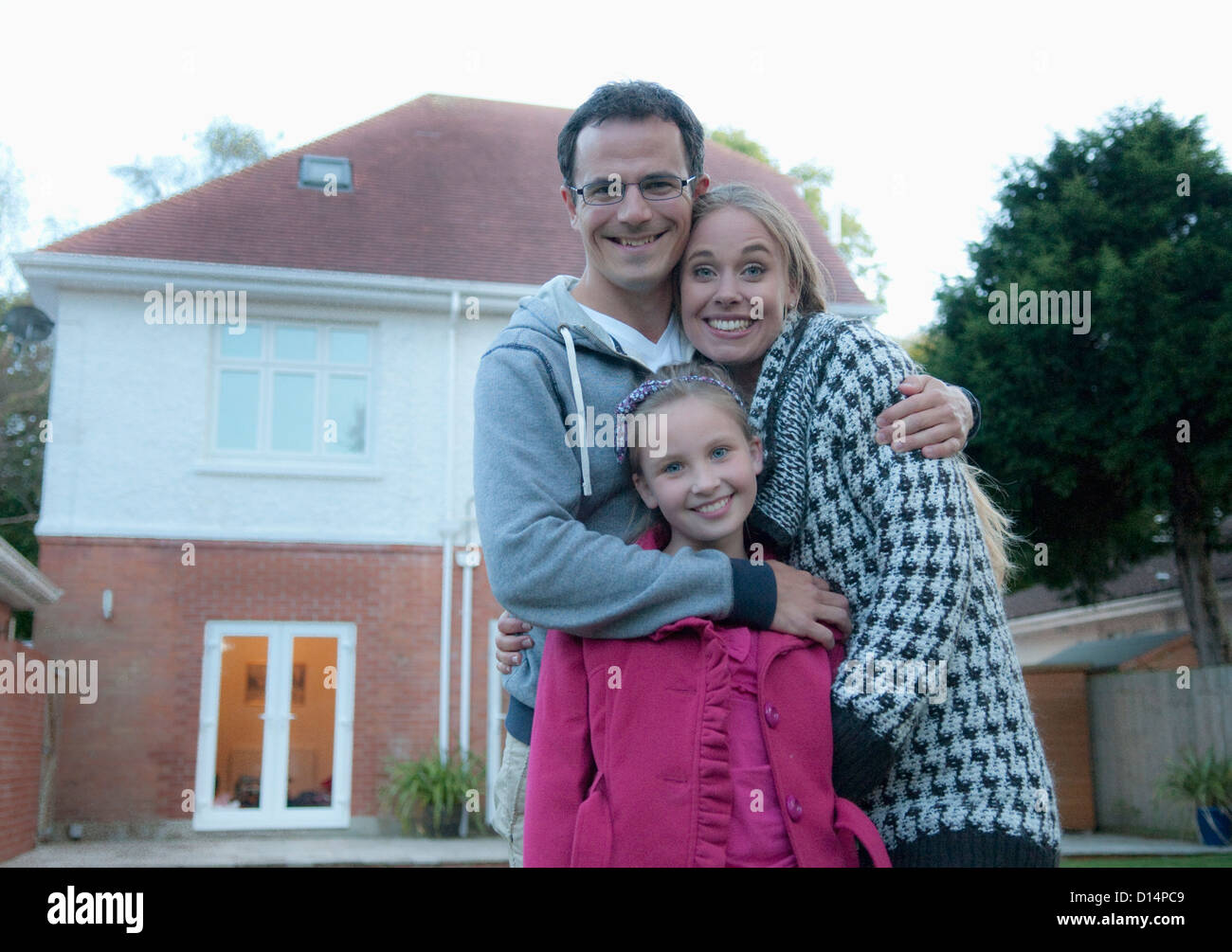Family smiling together outside house Stock Photo - Alamy