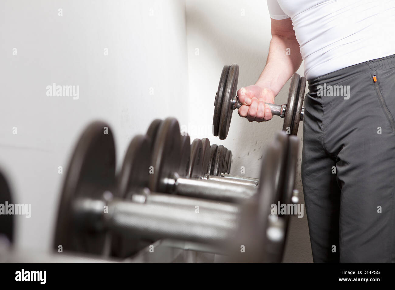 Man using free weights at gym Stock Photo - Alamy