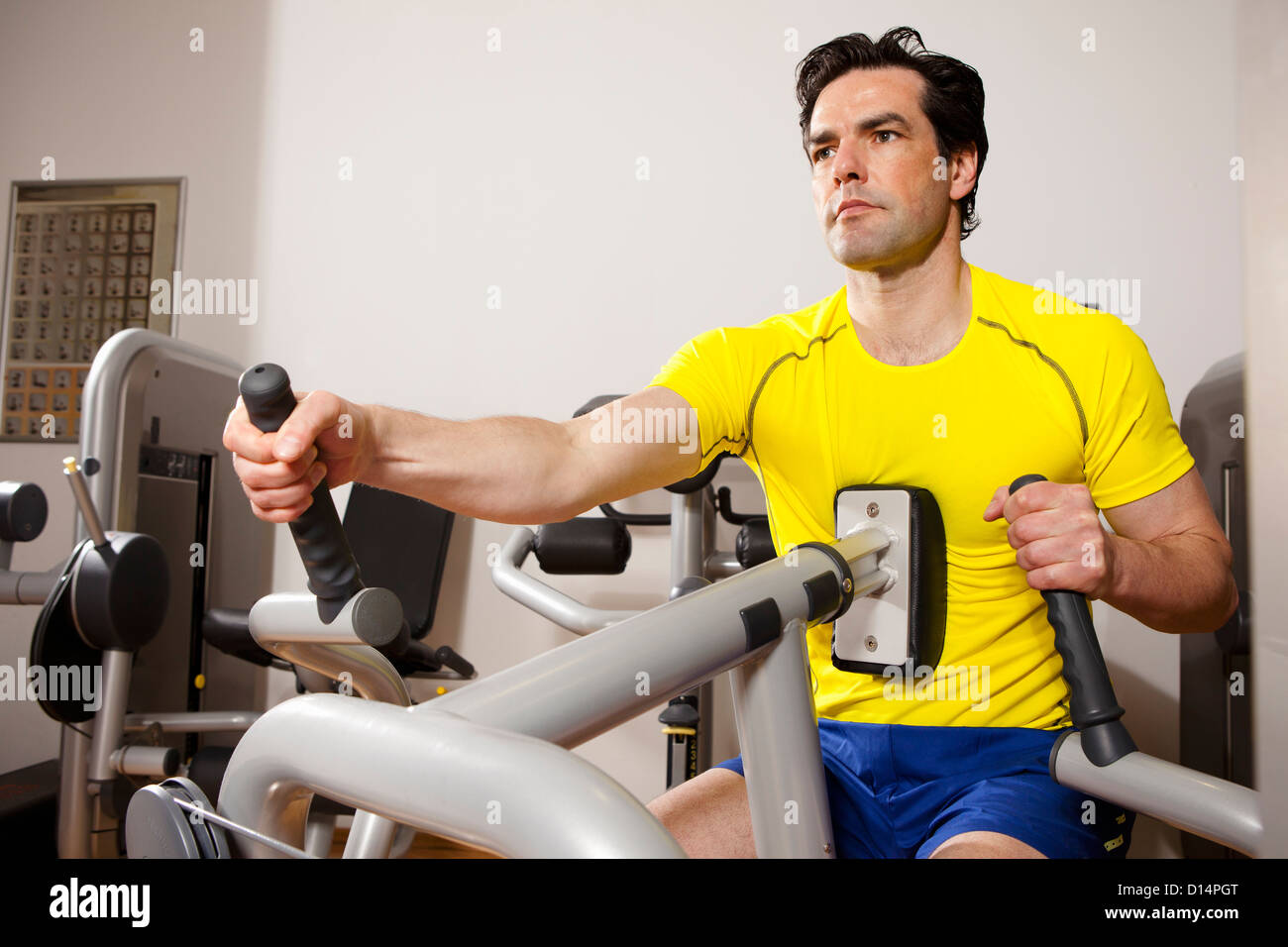 Man using exercise equipment at gym Stock Photo - Alamy
