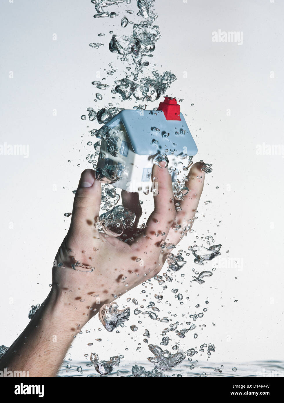 Hand grasping model house in water Stock Photo - Alamy
