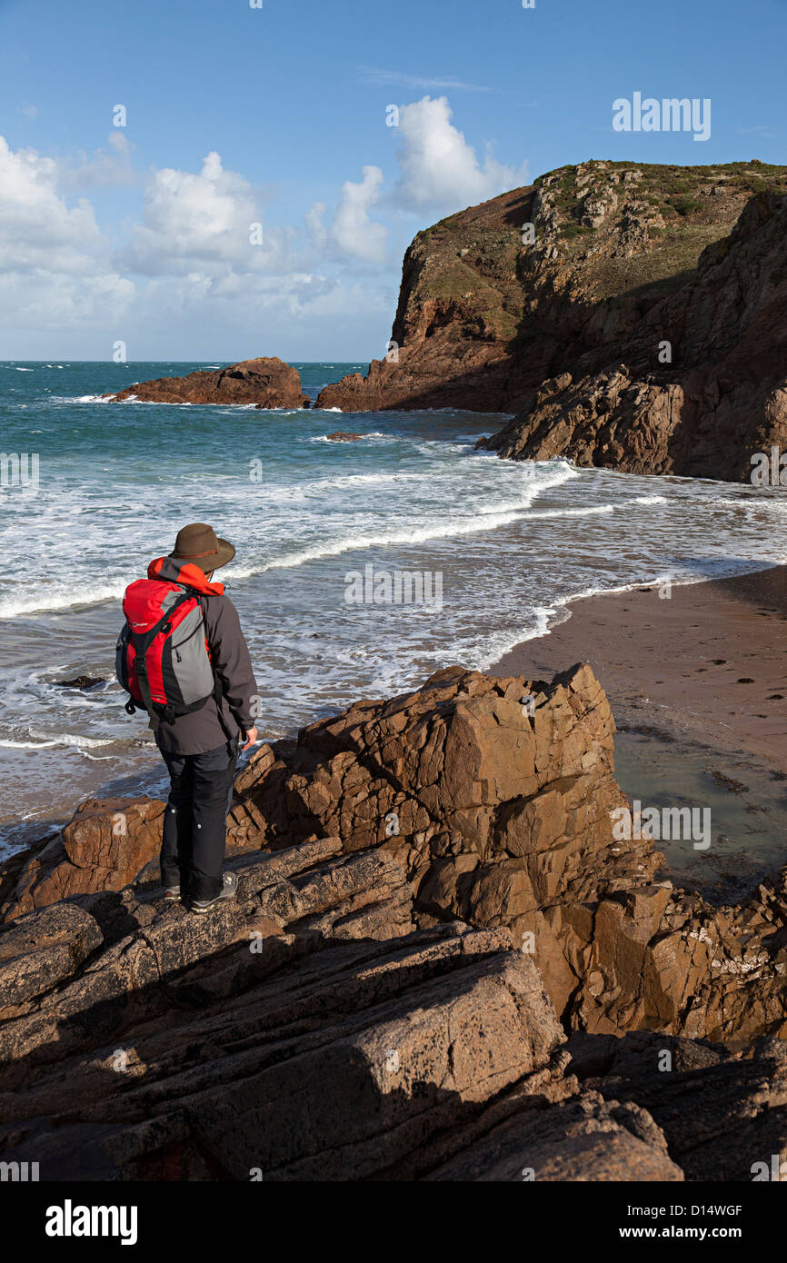 Person standing on rocks at Plemont beach, Jersey; Channel Islands, UK ...