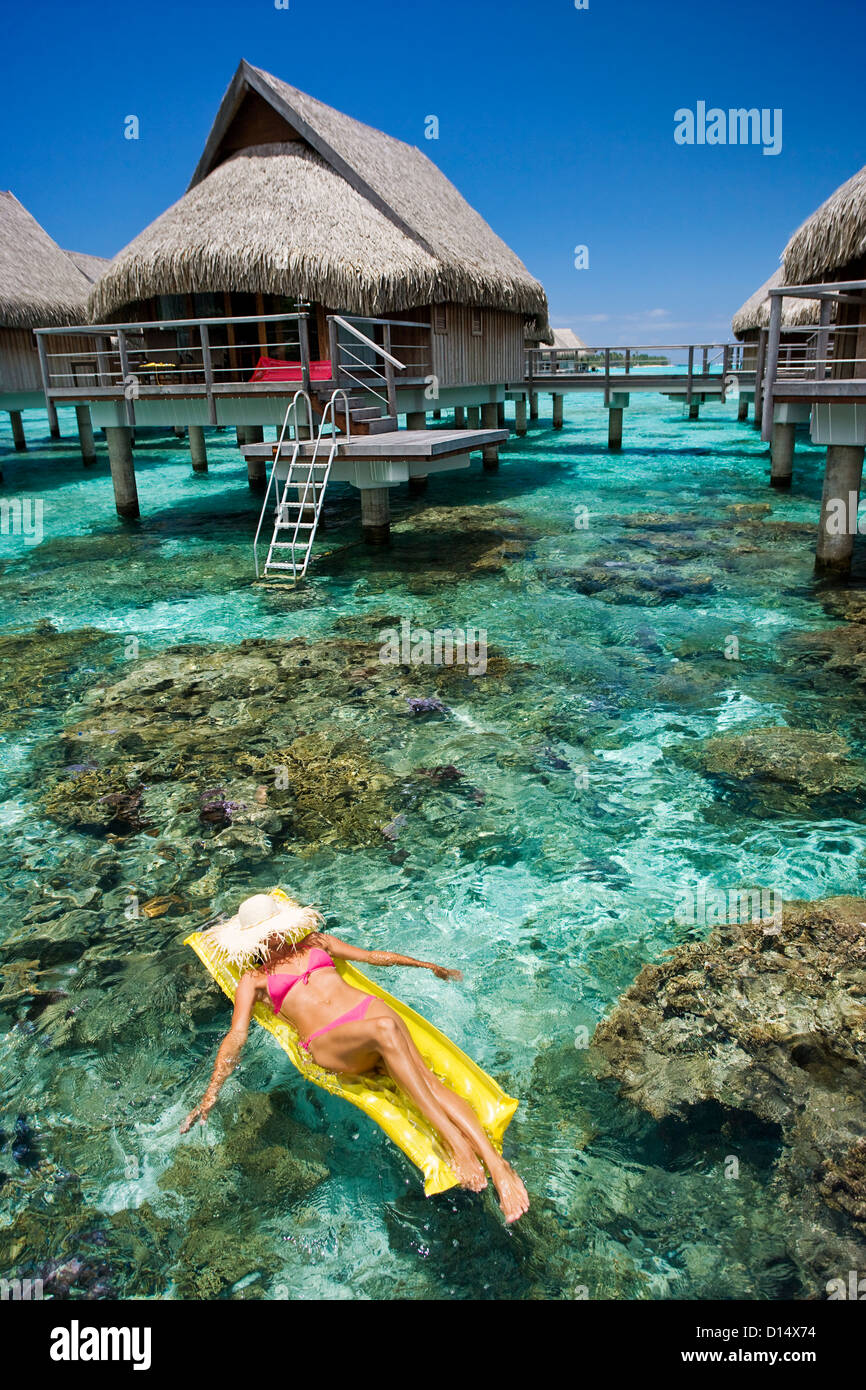 French Polynesia, Moorea, Woman Sunbathing On Inflatable Raft Over ...