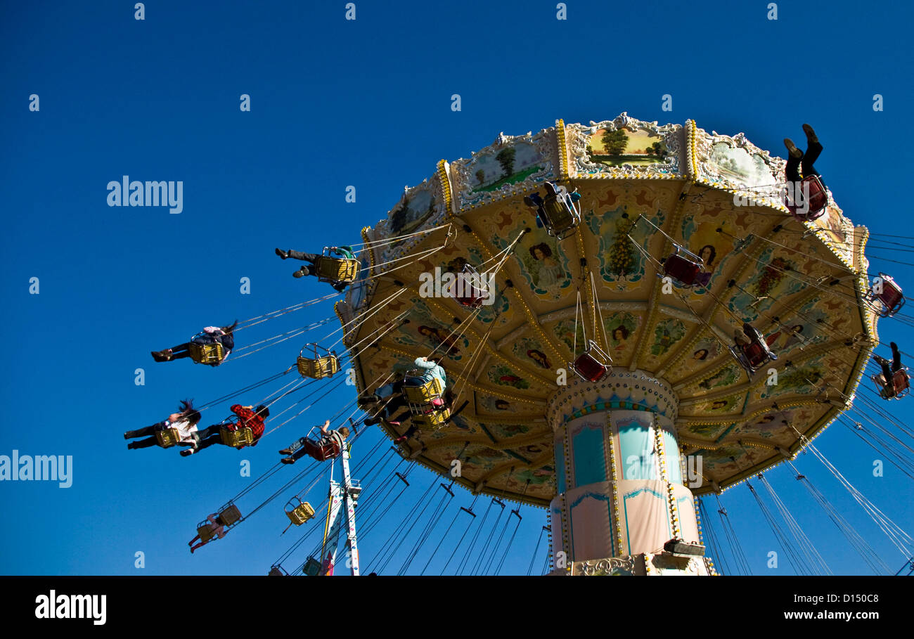 Fairground swing carousel thrill ride spinning fast against clear blue ...