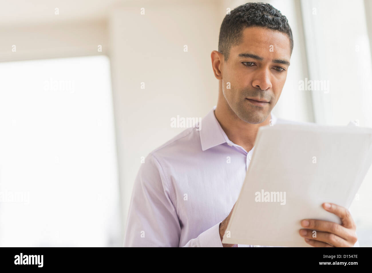 USA, New Jersey, Jersey City, Male business executive reading document ...