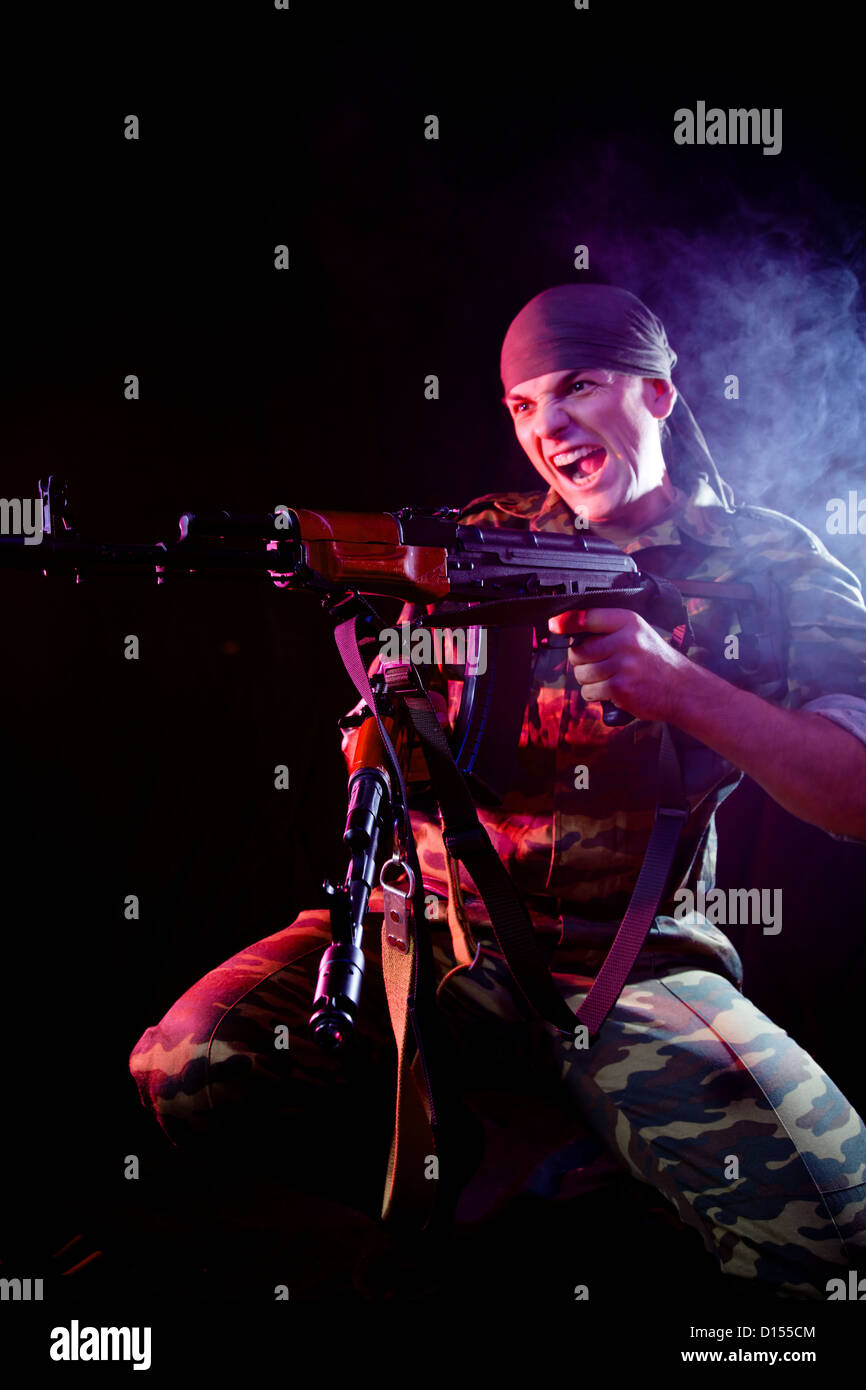 Aggressive soldier shooting his enemies, focus on weapon Stock Photo ...