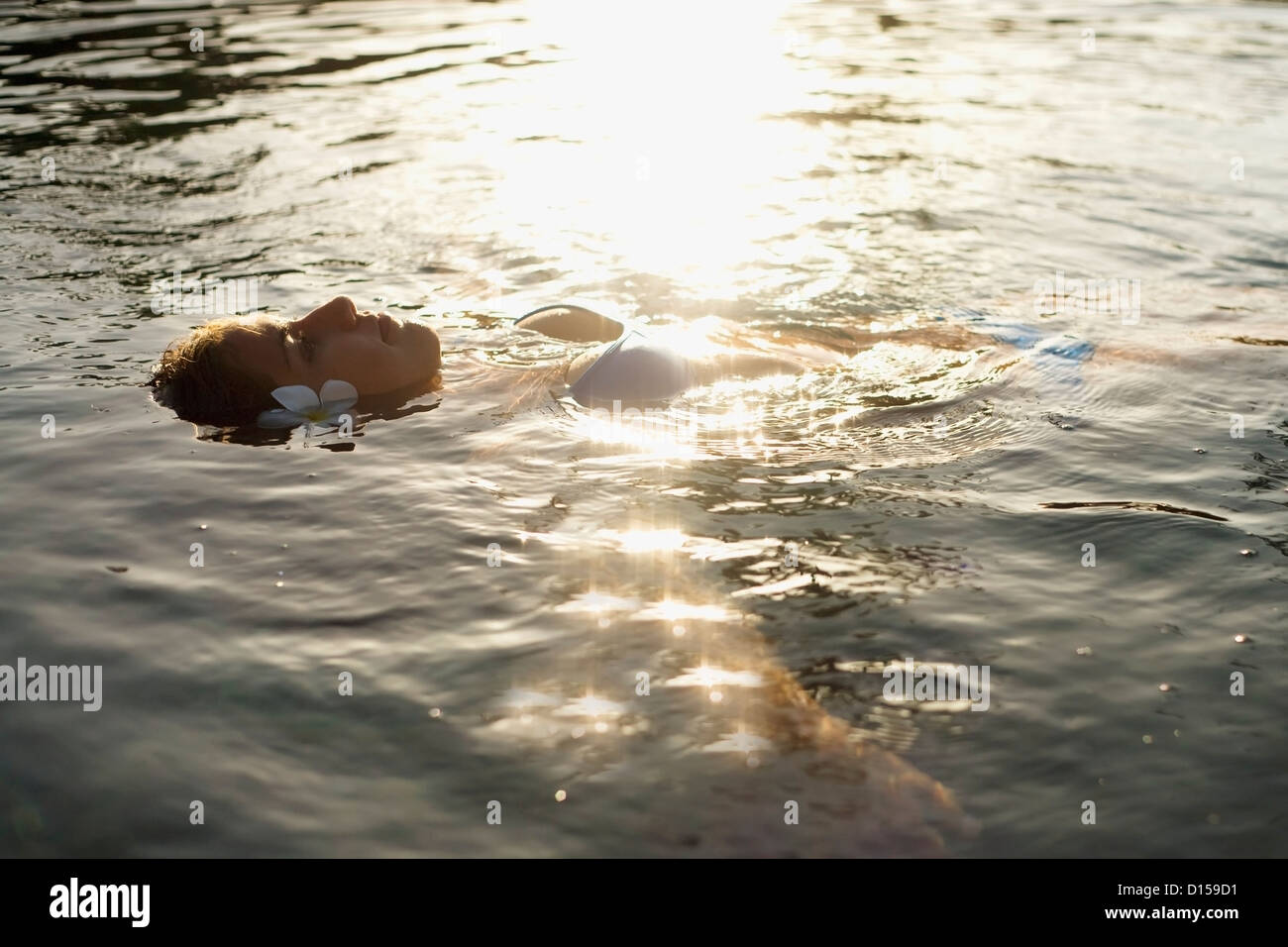 Hawaii, Oahu, Beautiful Woman Floating In The Water As The Sun Sets ...