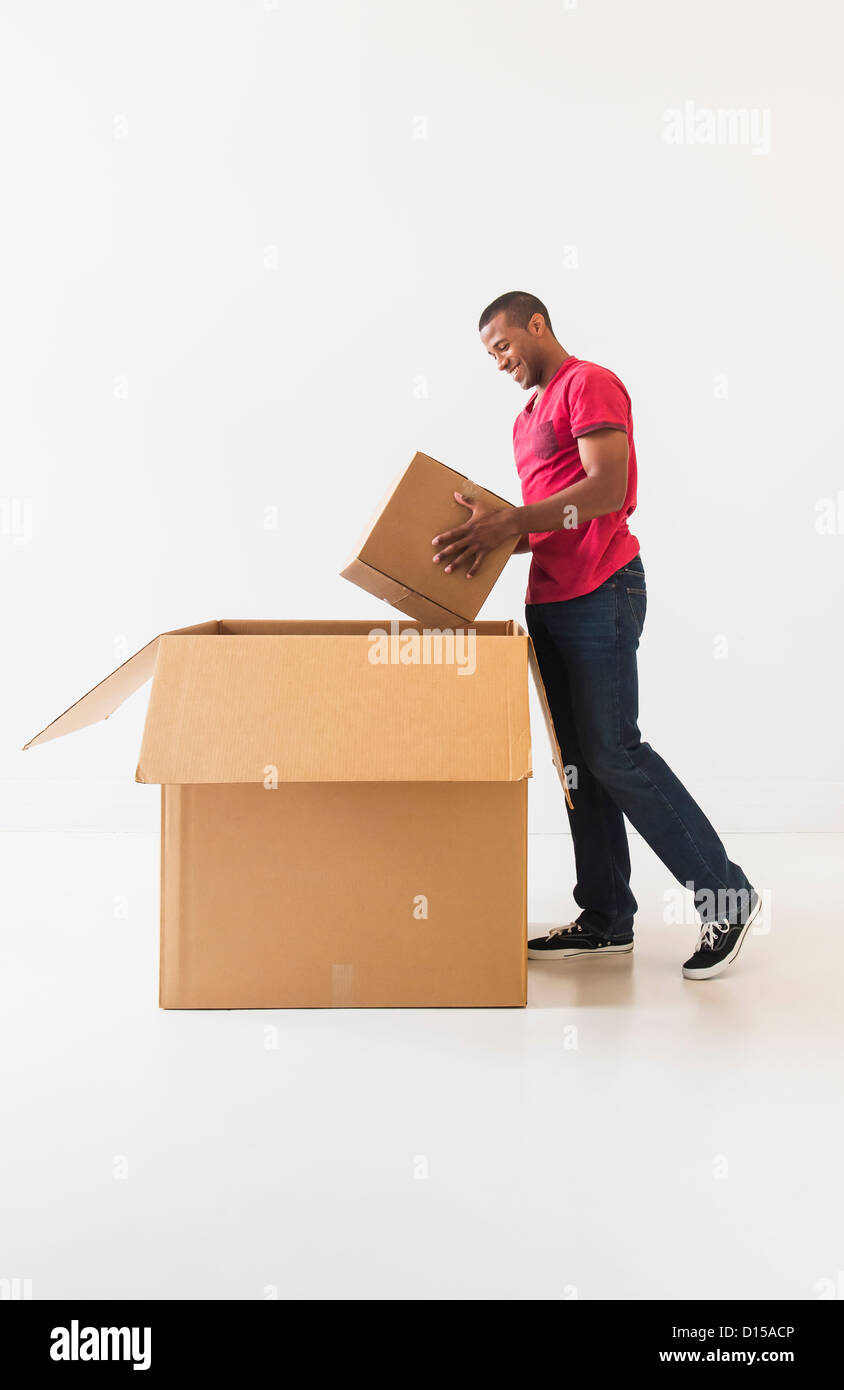Studio shot of young man with large cardboard box Stock Photo - Alamy
