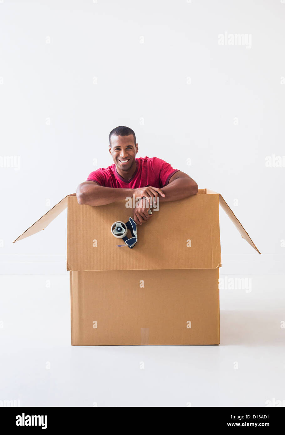 Studio shot of young man with large cardboard box Stock Photo - Alamy
