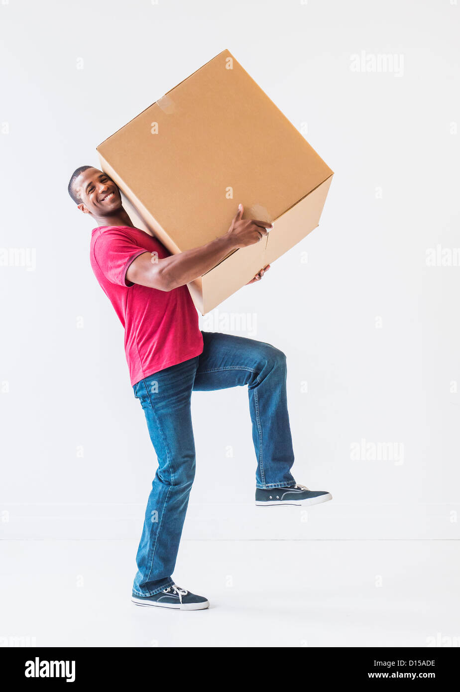 Studio shot of young man with large cardboard box Stock Photo - Alamy
