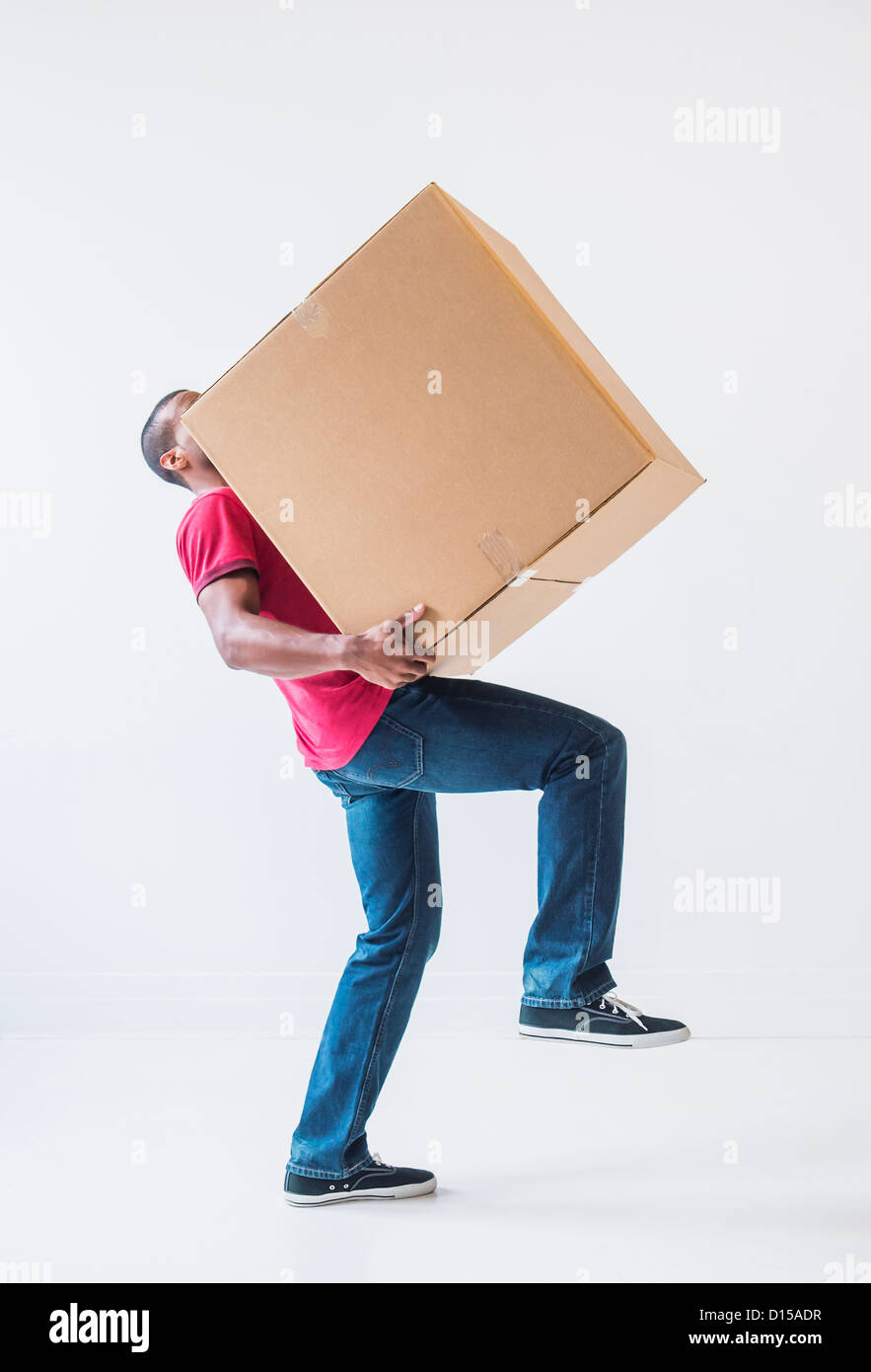 Studio shot of young man with large cardboard box Stock Photo - Alamy