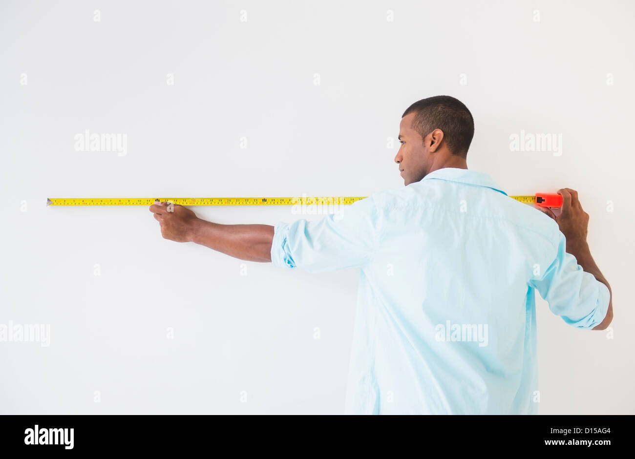 Young man measuring white wall Stock Photo - Alamy