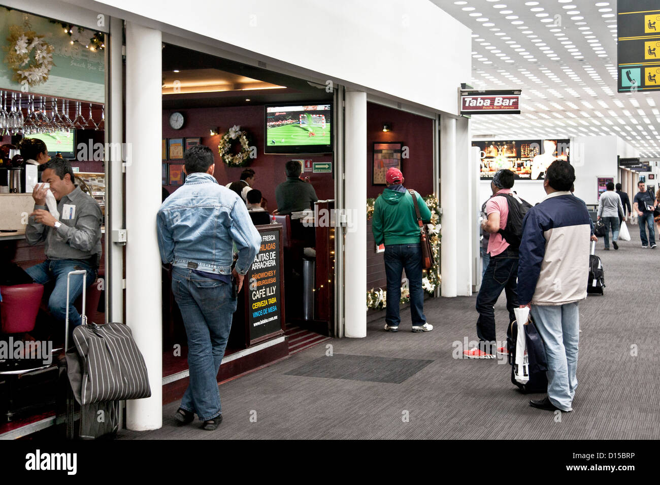 male travelers gathered around outside concourse bar to watch soccer ...